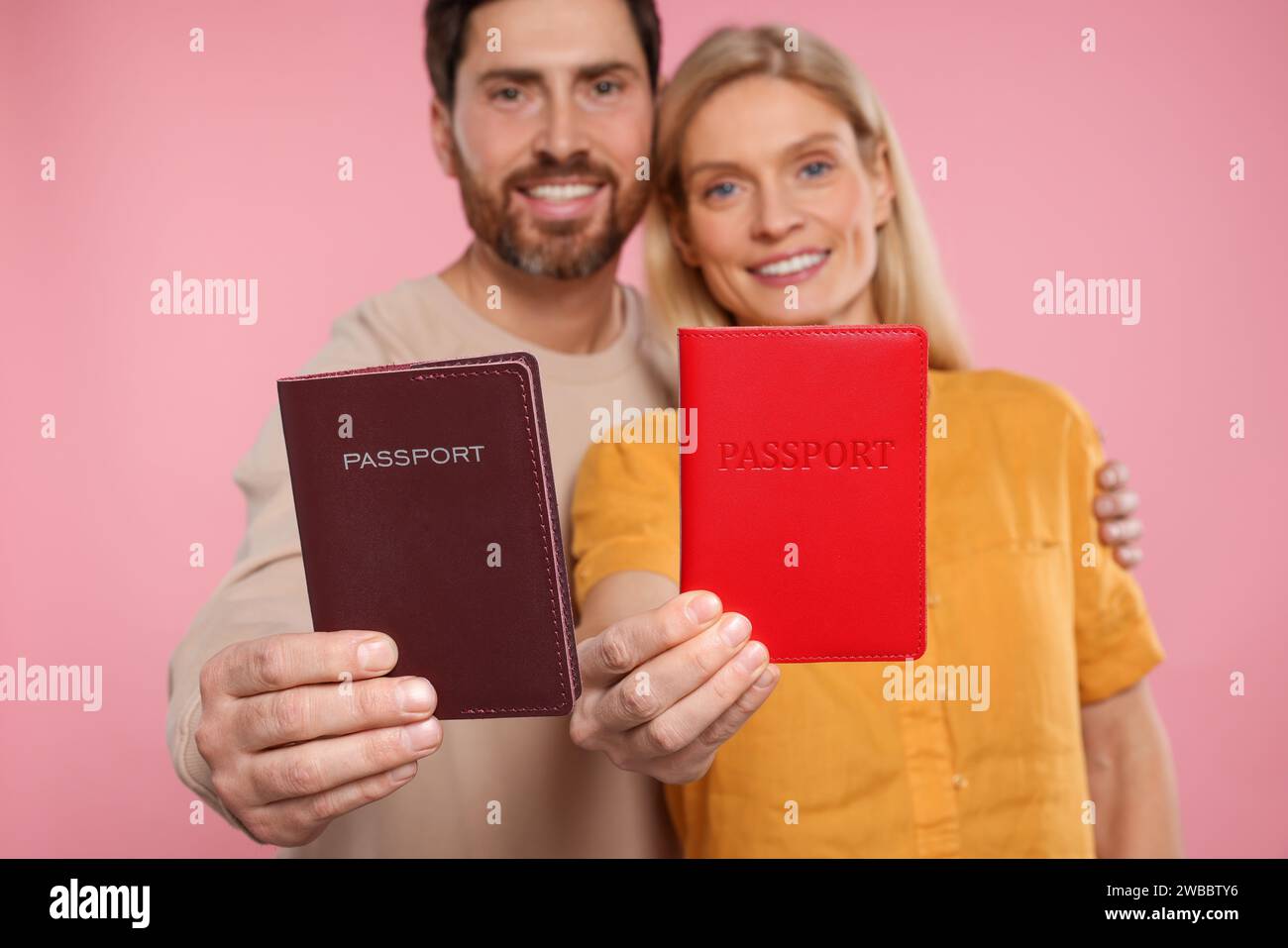 Immigration. Happy couple with passports on pink background, selective ...