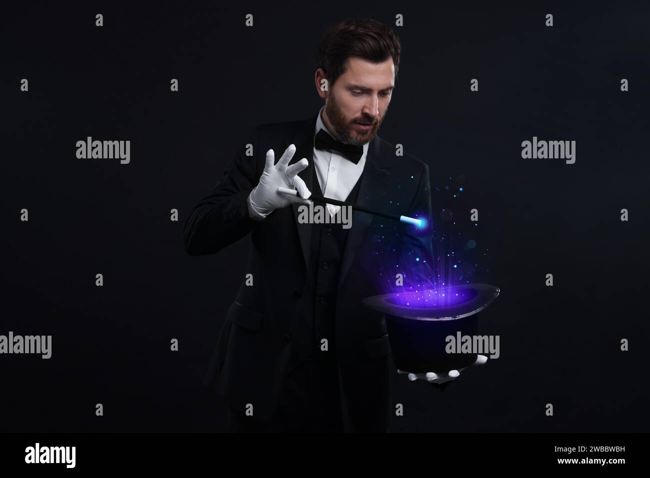 Magician showing trick with top hat and wand on black background Stock ...