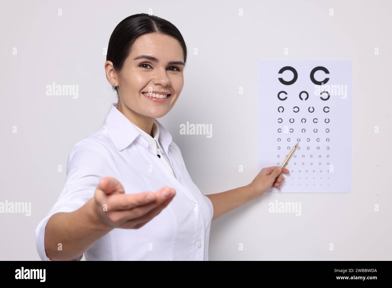 Ophthalmologist pointing at vision test chart on white wall Stock Photo ...