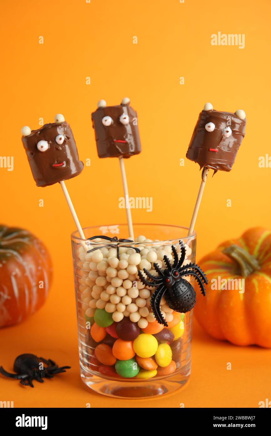 Delicious candies decorated as monsters on orange background. Halloween ...