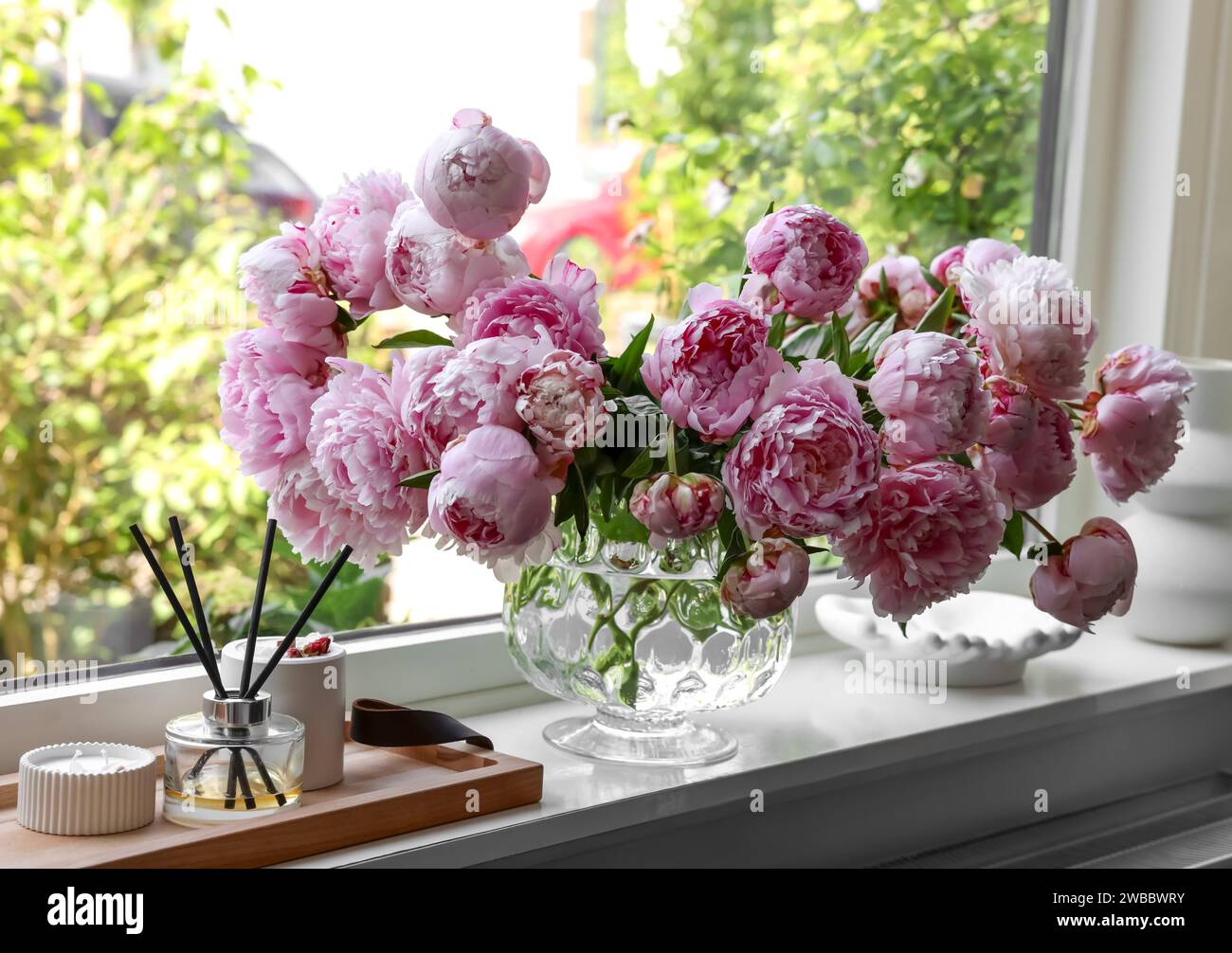 Beautiful pink peonies in vase on window sill. Interior design Stock Photo - Alamy
