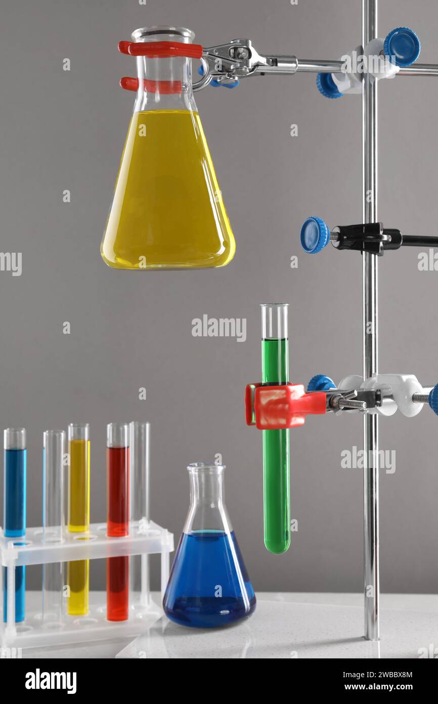 Retort stand and laboratory glassware with liquids on table against ...