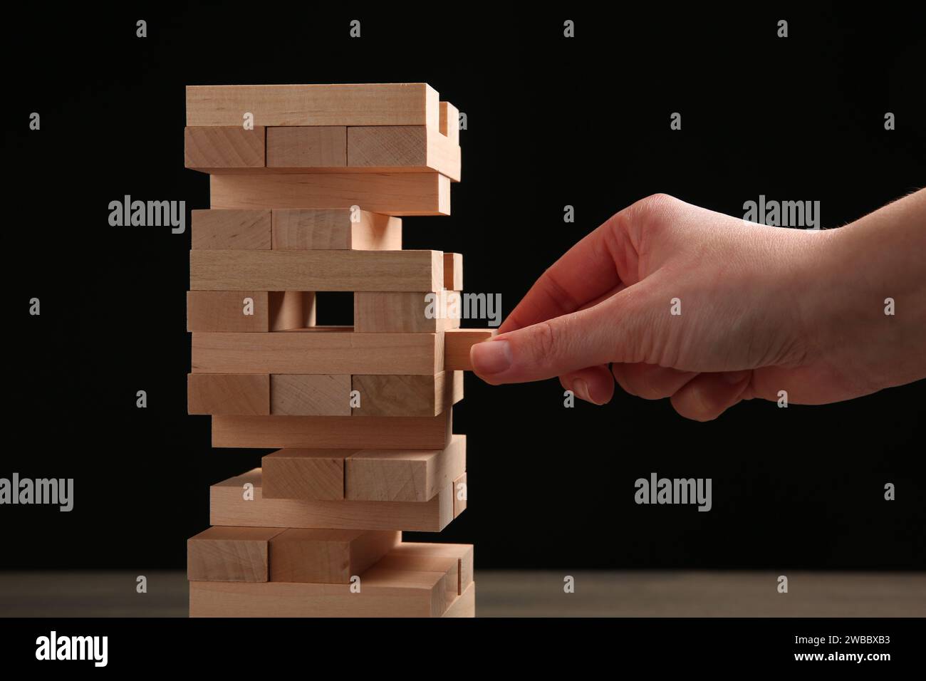 Woman playing Jenga at table against black background, closeup Stock ...