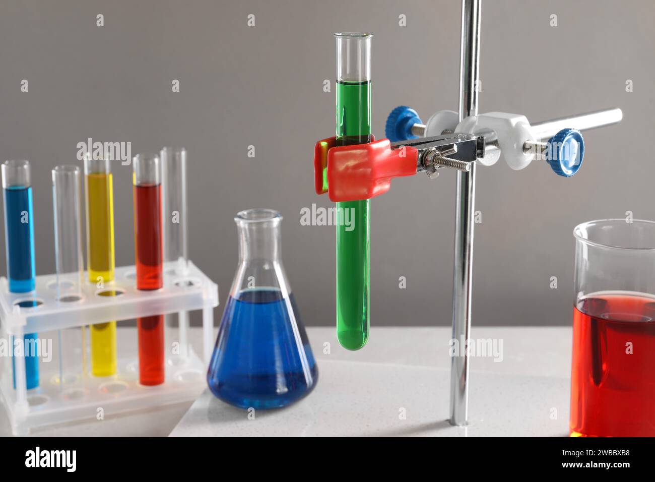 Retort stand and laboratory glassware with liquids on table against ...
