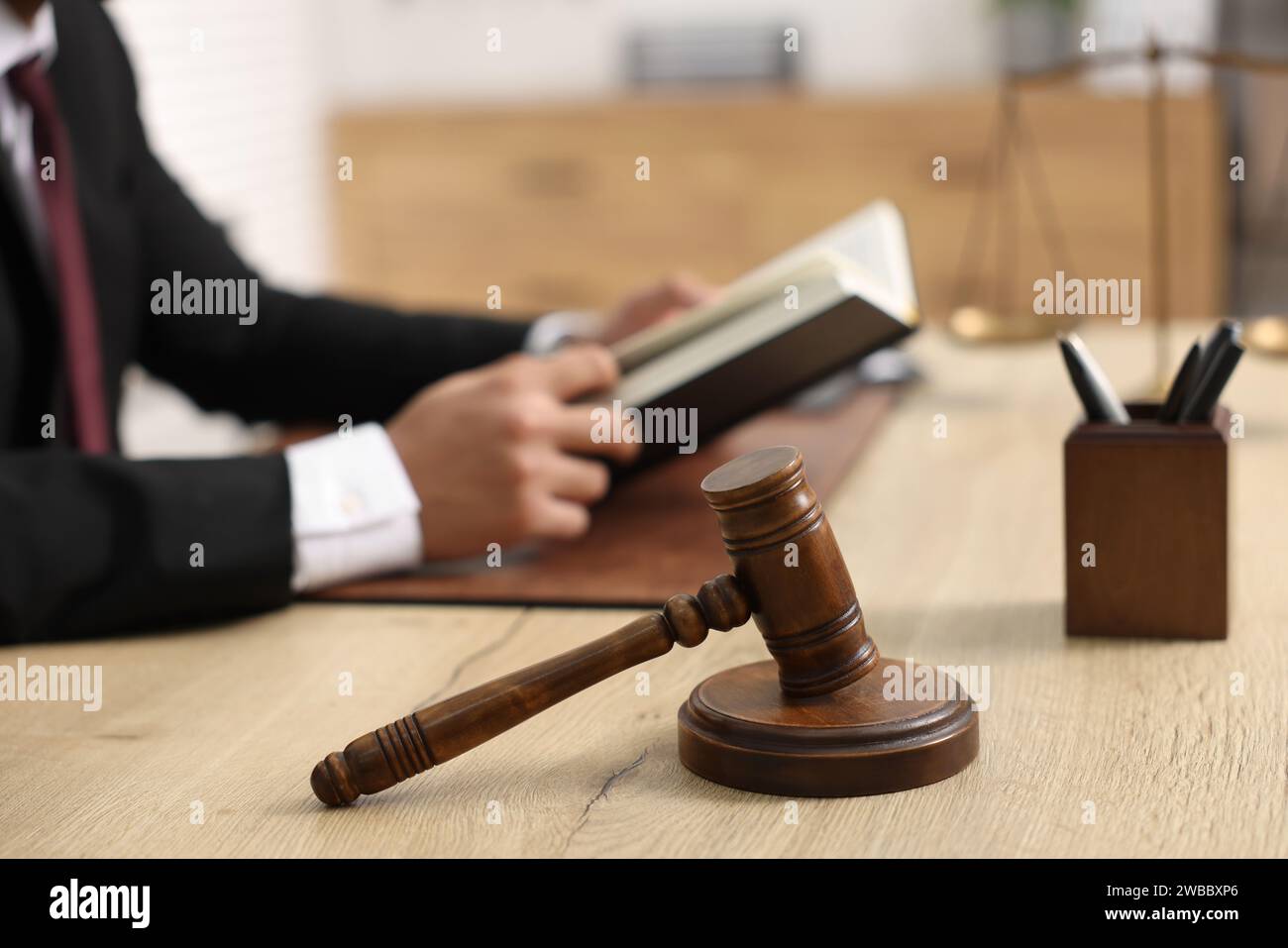 Lawyer reading book at table in office, focus on gavel Stock Photo - Alamy