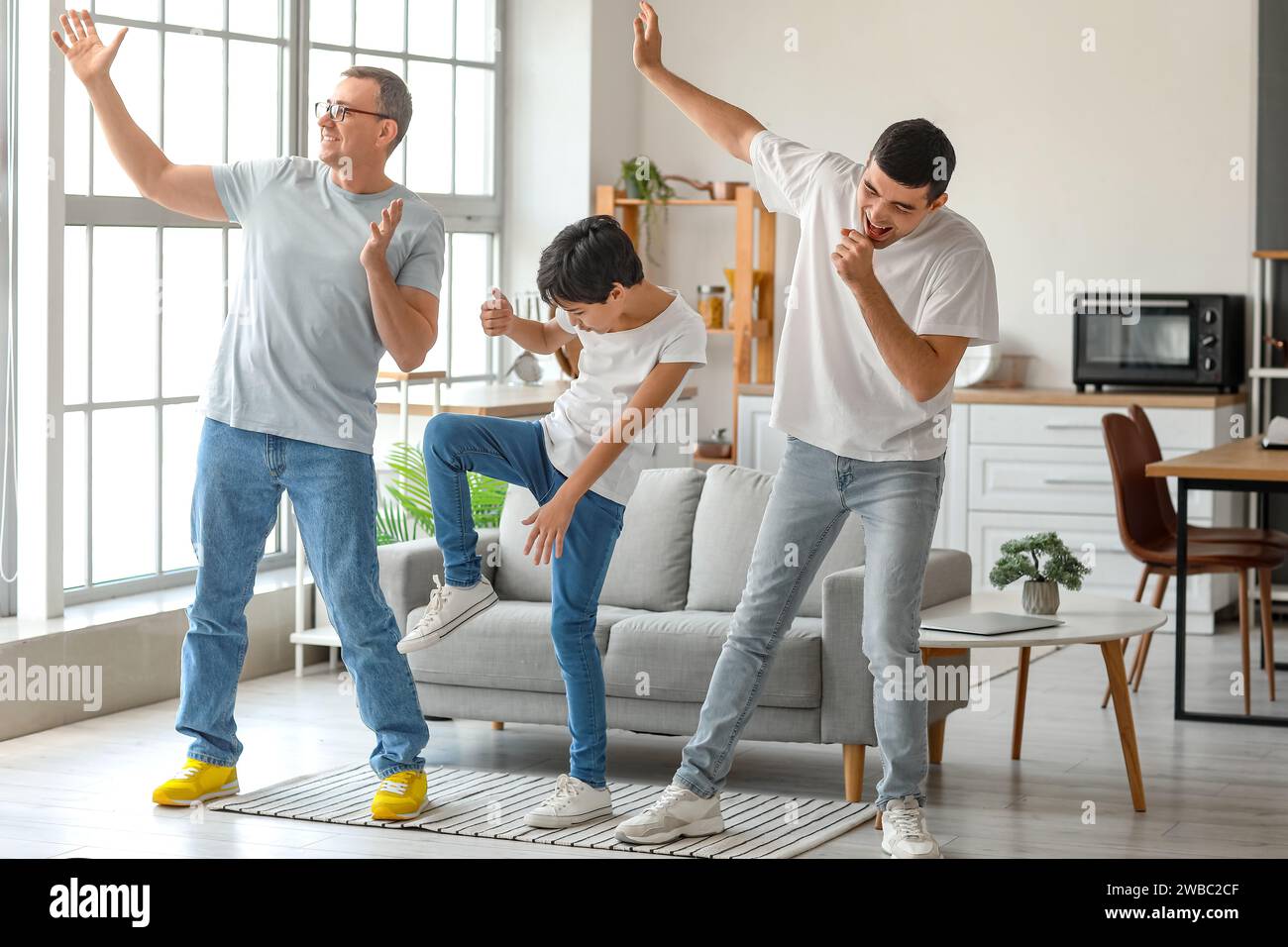Happy little boy with his dad and grandfather dancing at home Stock ...