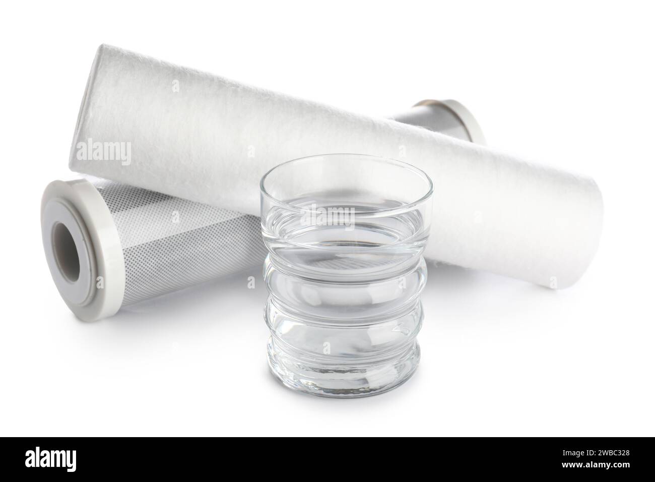 Glass of liquid and water filter cartridges isolated on white ...