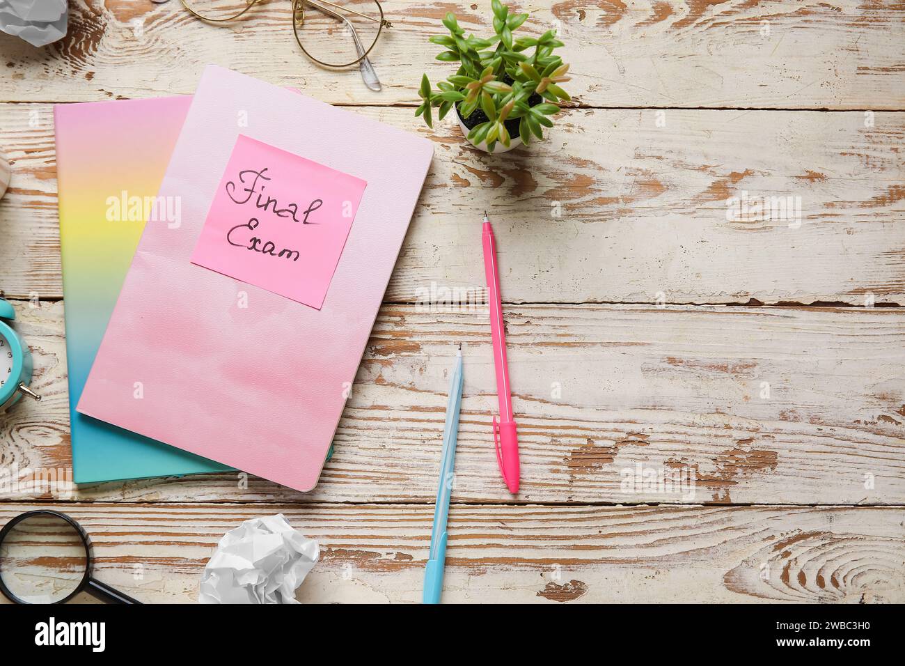 Sticky note with text FINAL EXAM, notebooks, eyeglasses and magnifier ...