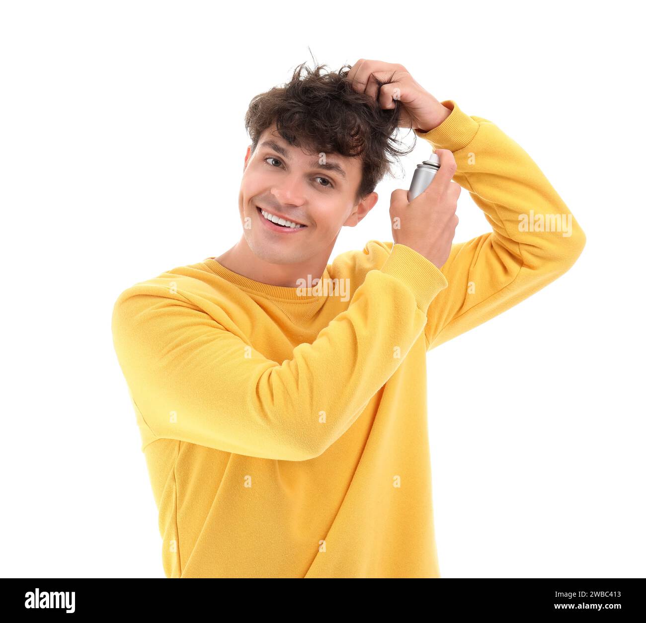 Handsome young man applying hair spray on his curly hair against white ...