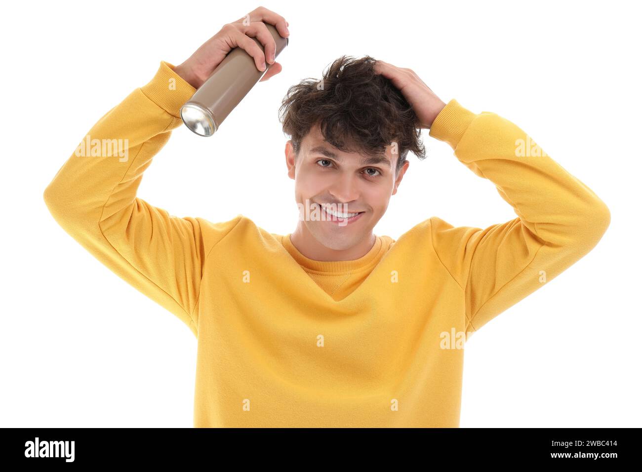 Handsome young man applying hair spray on his curly hair against white ...