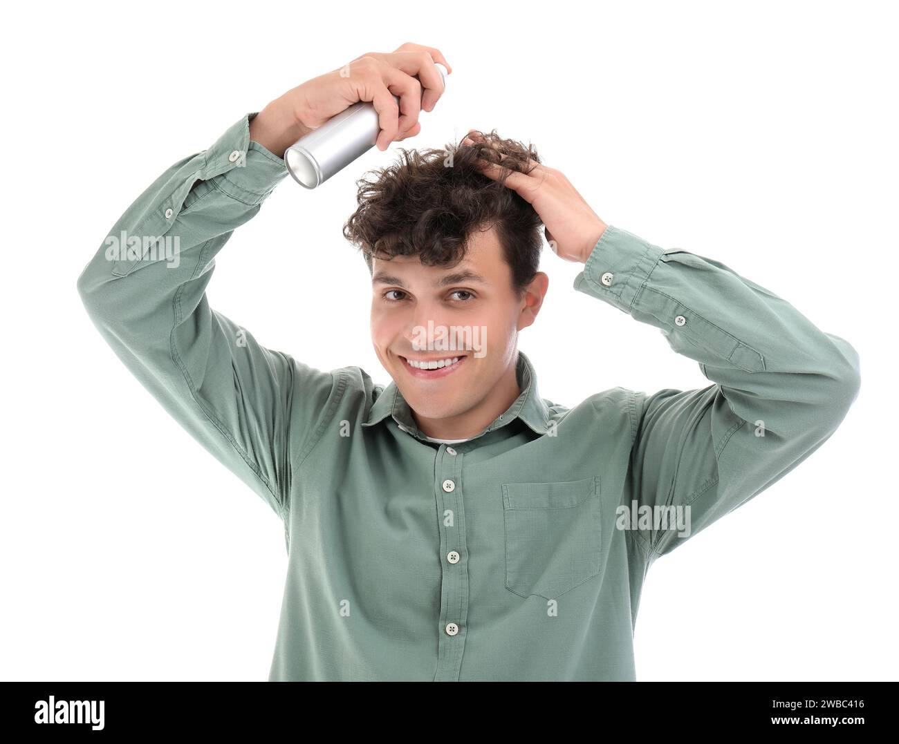Handsome young man applying hair spray on his curly hair against white ...