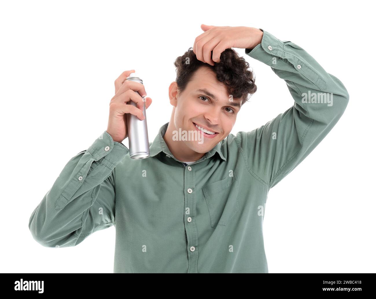 Handsome young man applying hair spray on his curly hair against white ...