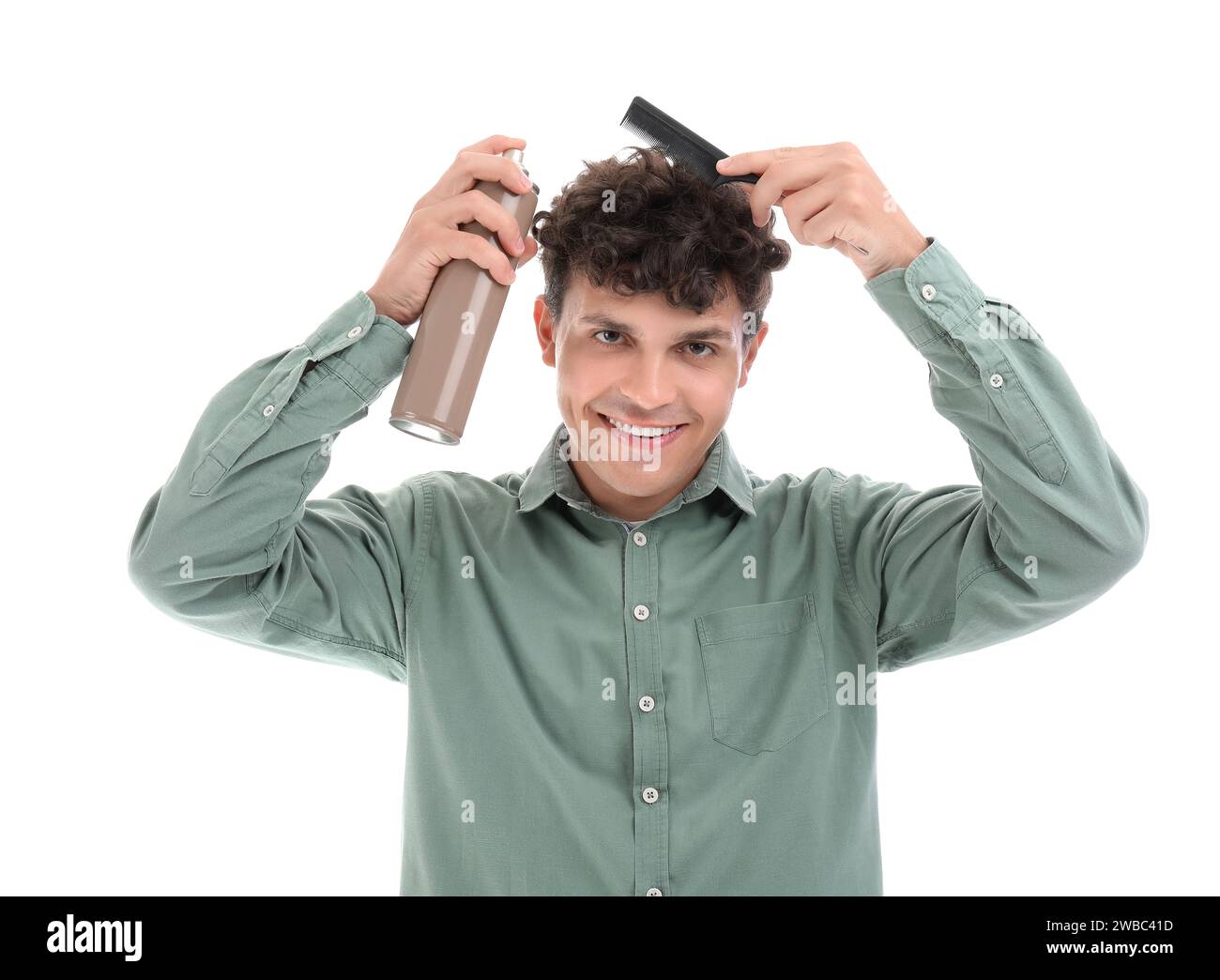 Handsome young man applying hair spray on his curly hair against white ...