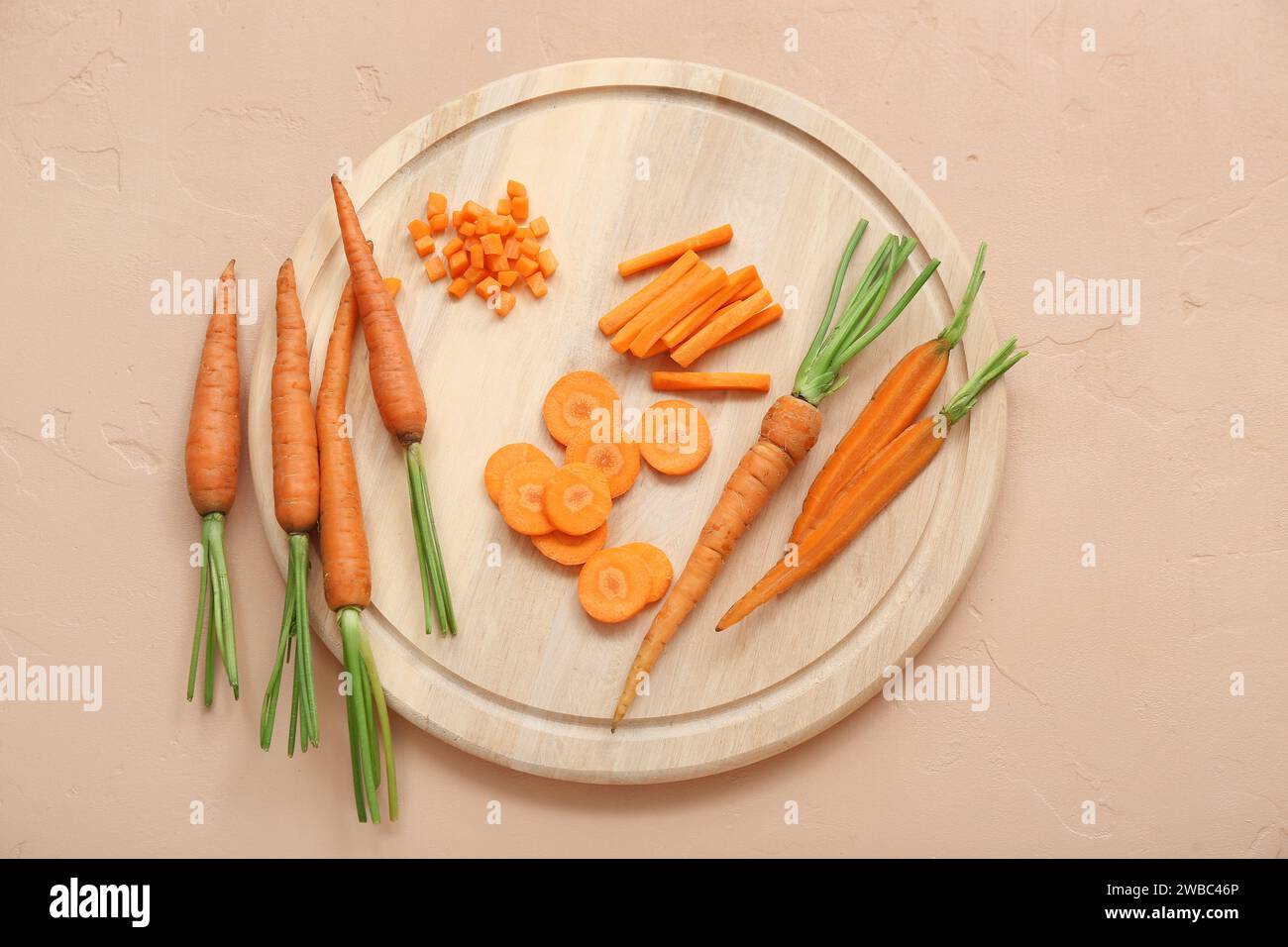 Wooden board with fresh carrots and slices on beige background Stock ...