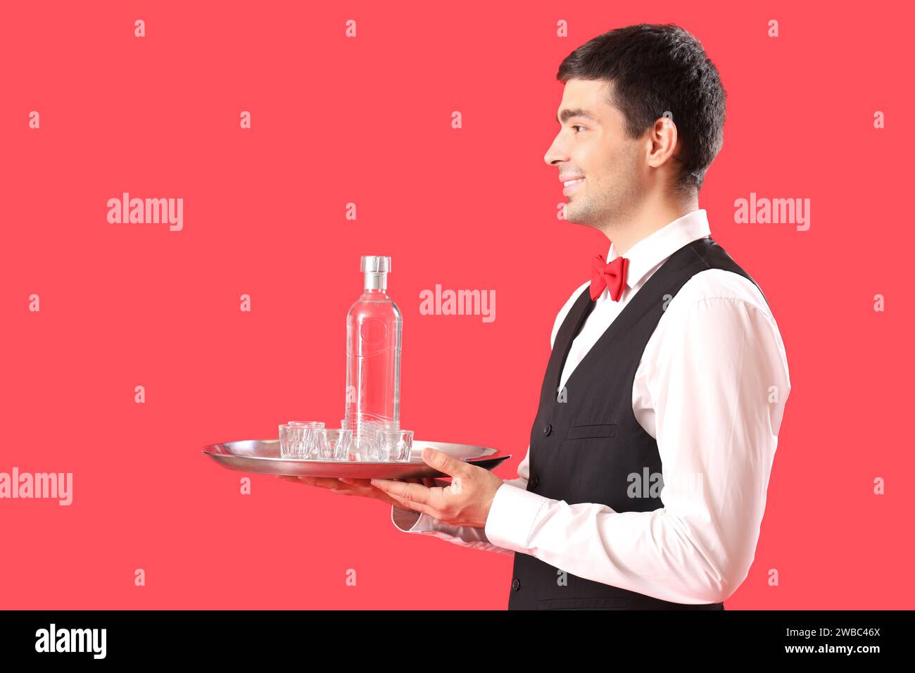 Male waiter with glasses and bottle of vodka on red background Stock ...