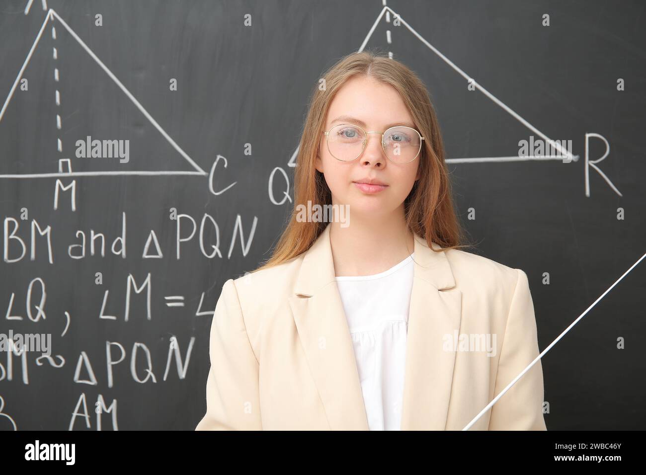 Young math teacher with pointer near blackboard in classroom Stock ...