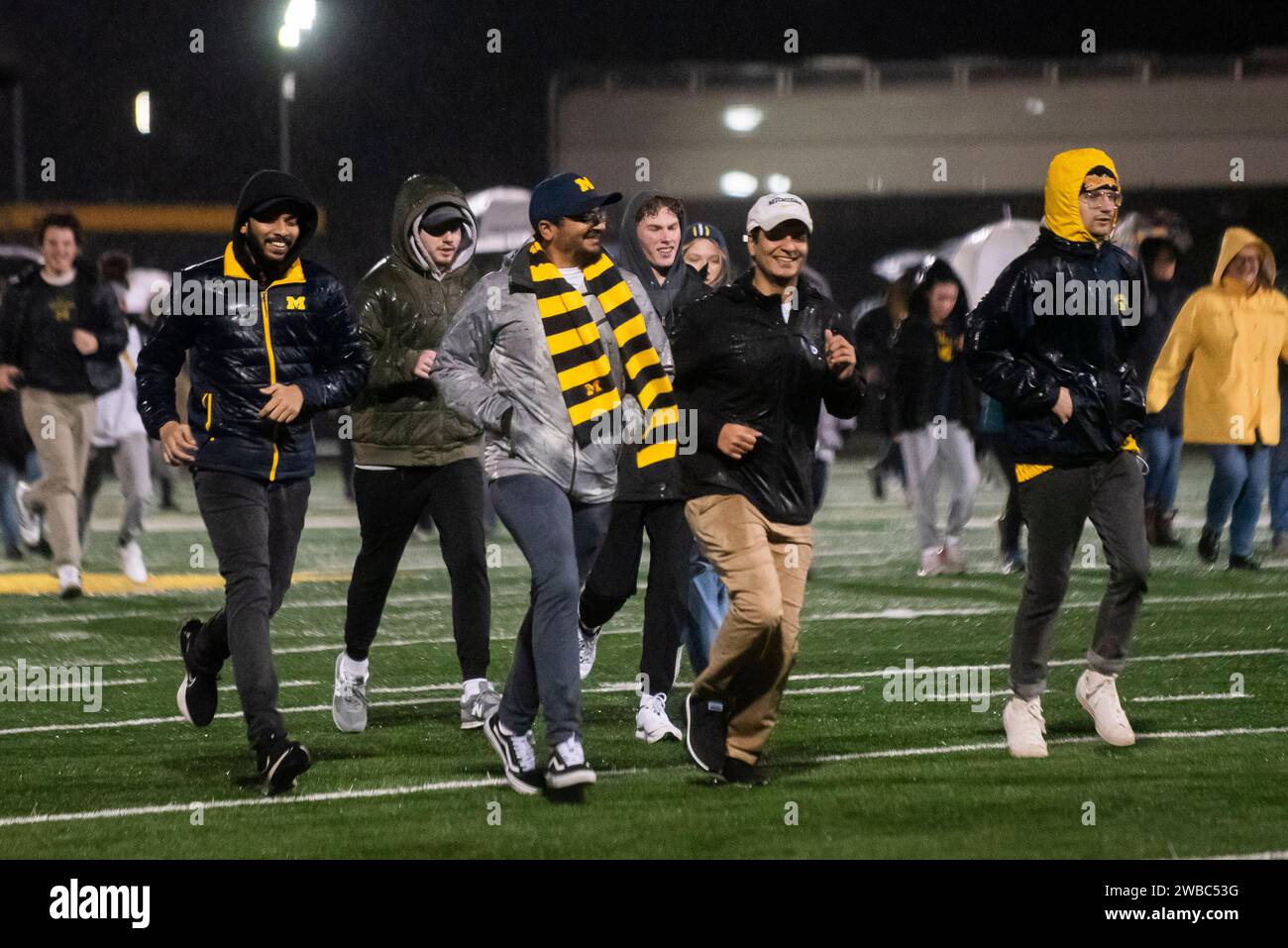 Michigan football fans sprint across a practice field to get a good ...