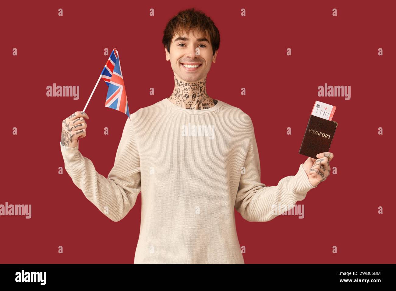 Handsome young man with UK flag and passport on red background ...