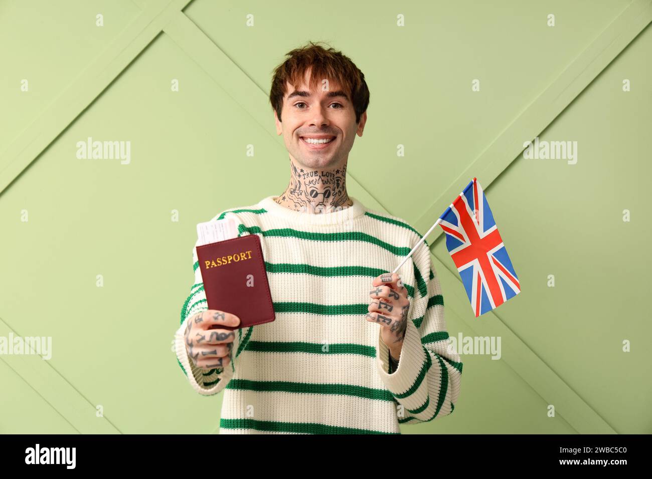 Handsome young man with UK flag and passport on green background ...