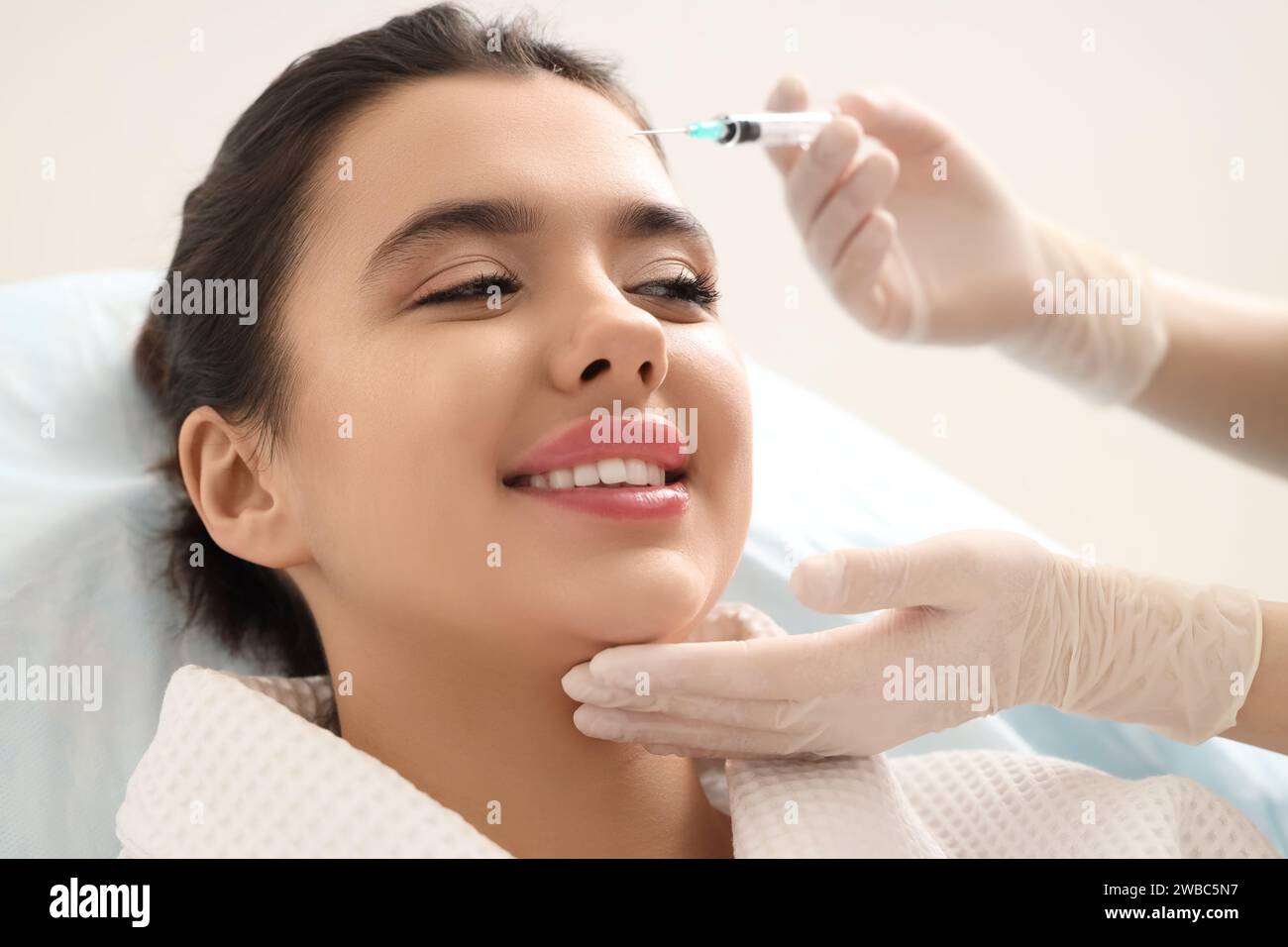 Smiling young woman receiving injection in beauty salon, closeup Stock ...