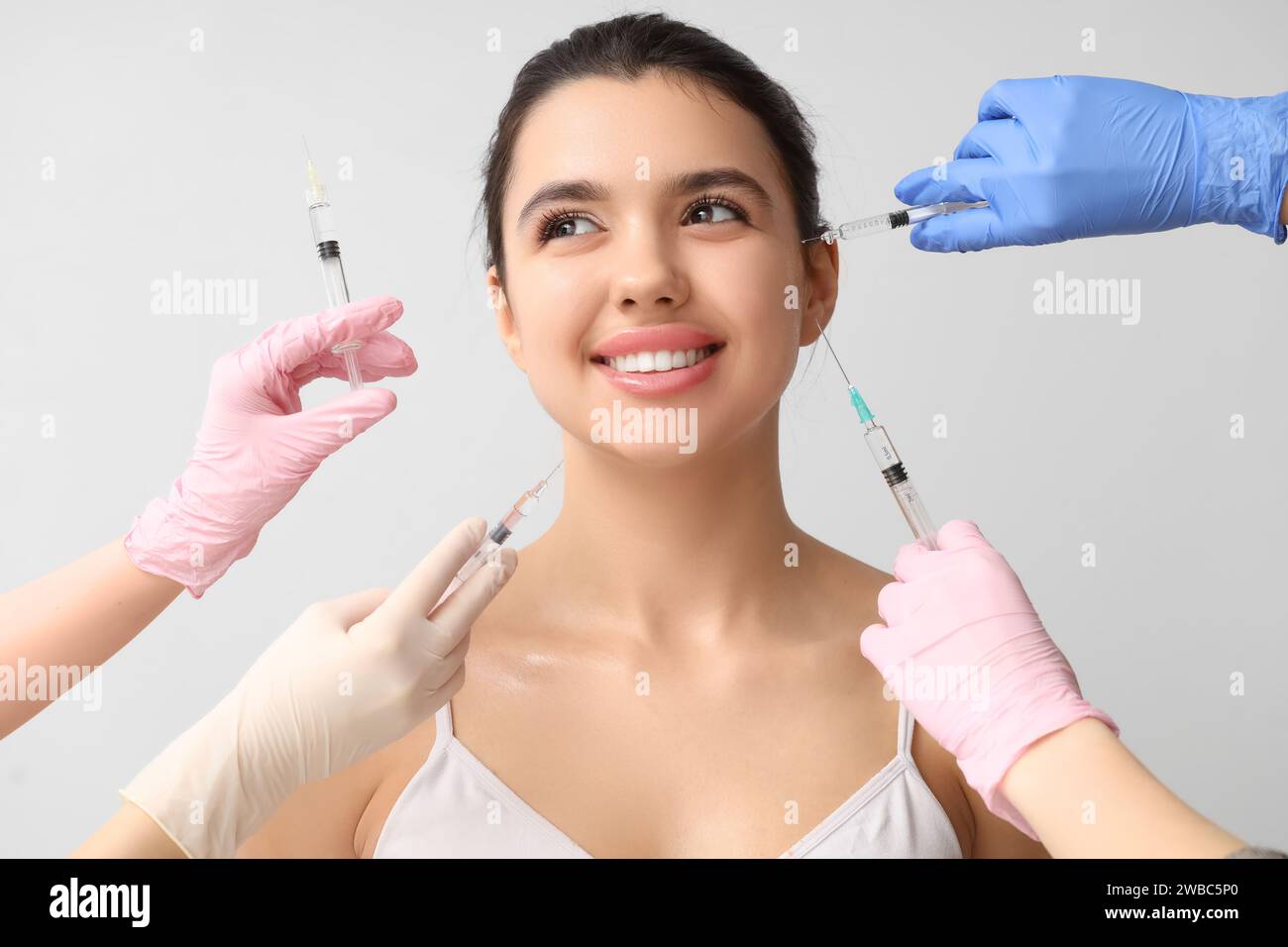 Young woman and hands with beauty injections on light background ...
