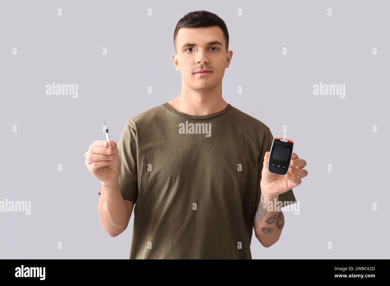 Diabetic young man with glucometer and insulin on light background ...