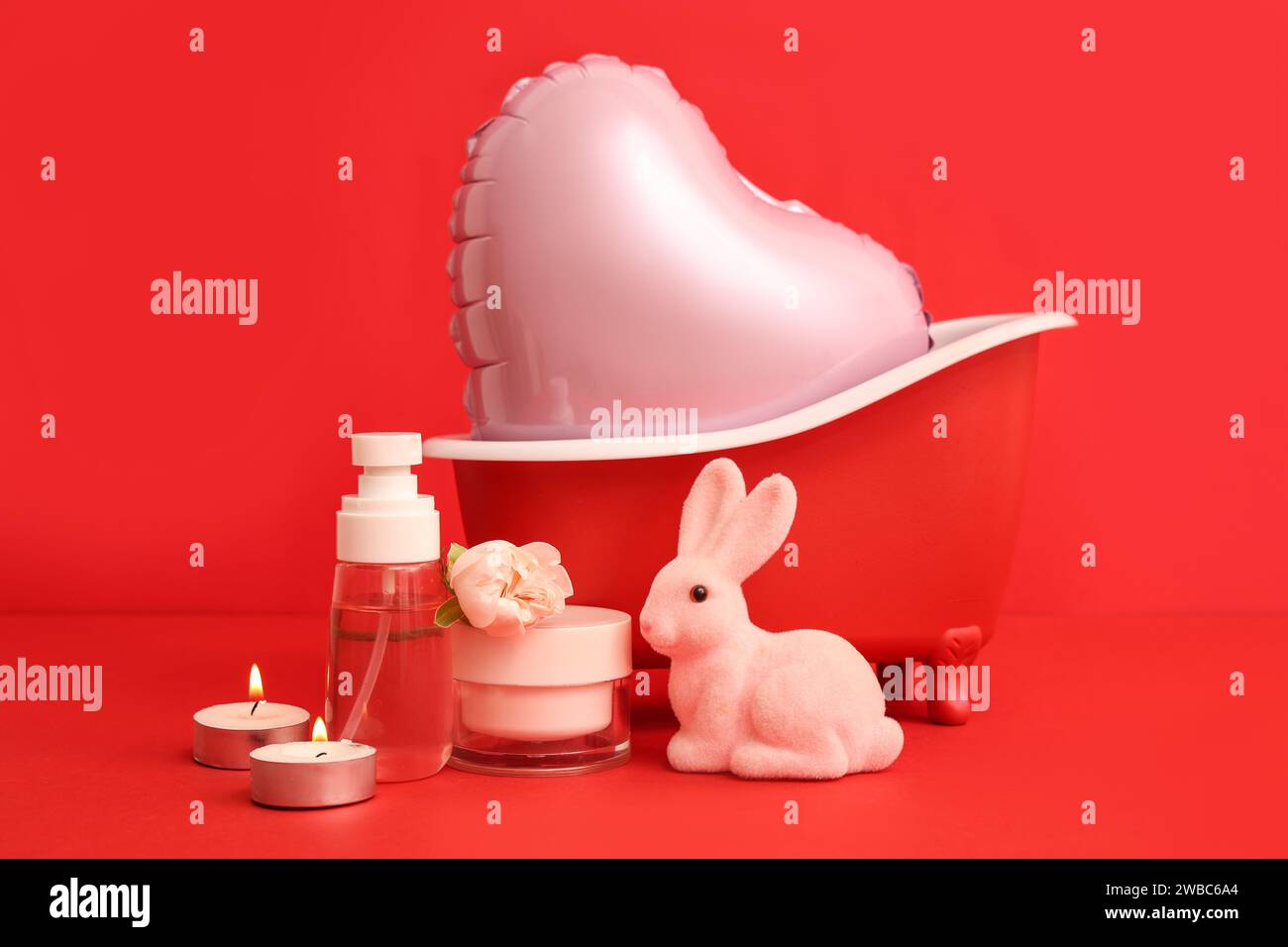 Mini bathtub with heart-shaped balloon, cosmetic products, candles and ...