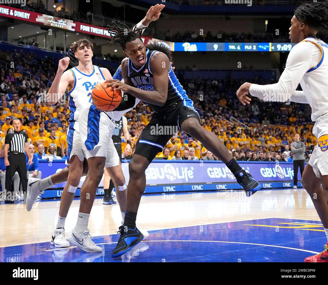 Duke 's Mark Mitchell, center, tries to get off a shot off between ...
