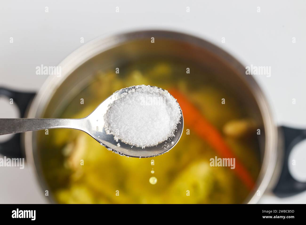 Metal spoon is used to add salt to chicken broth Stock Photo - Alamy