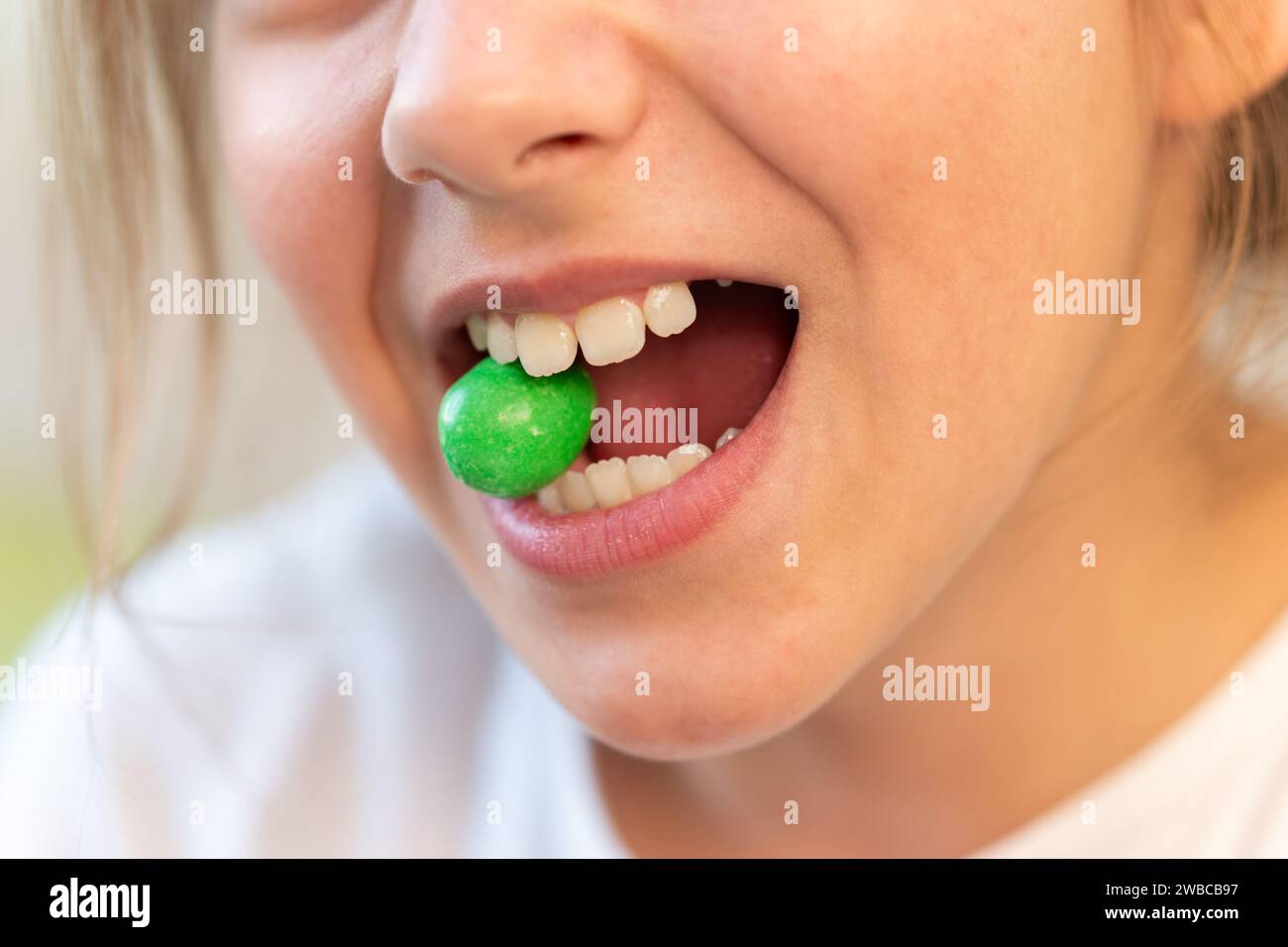 a green round candy in the teeth of a young teenage girl. Addiction of ...