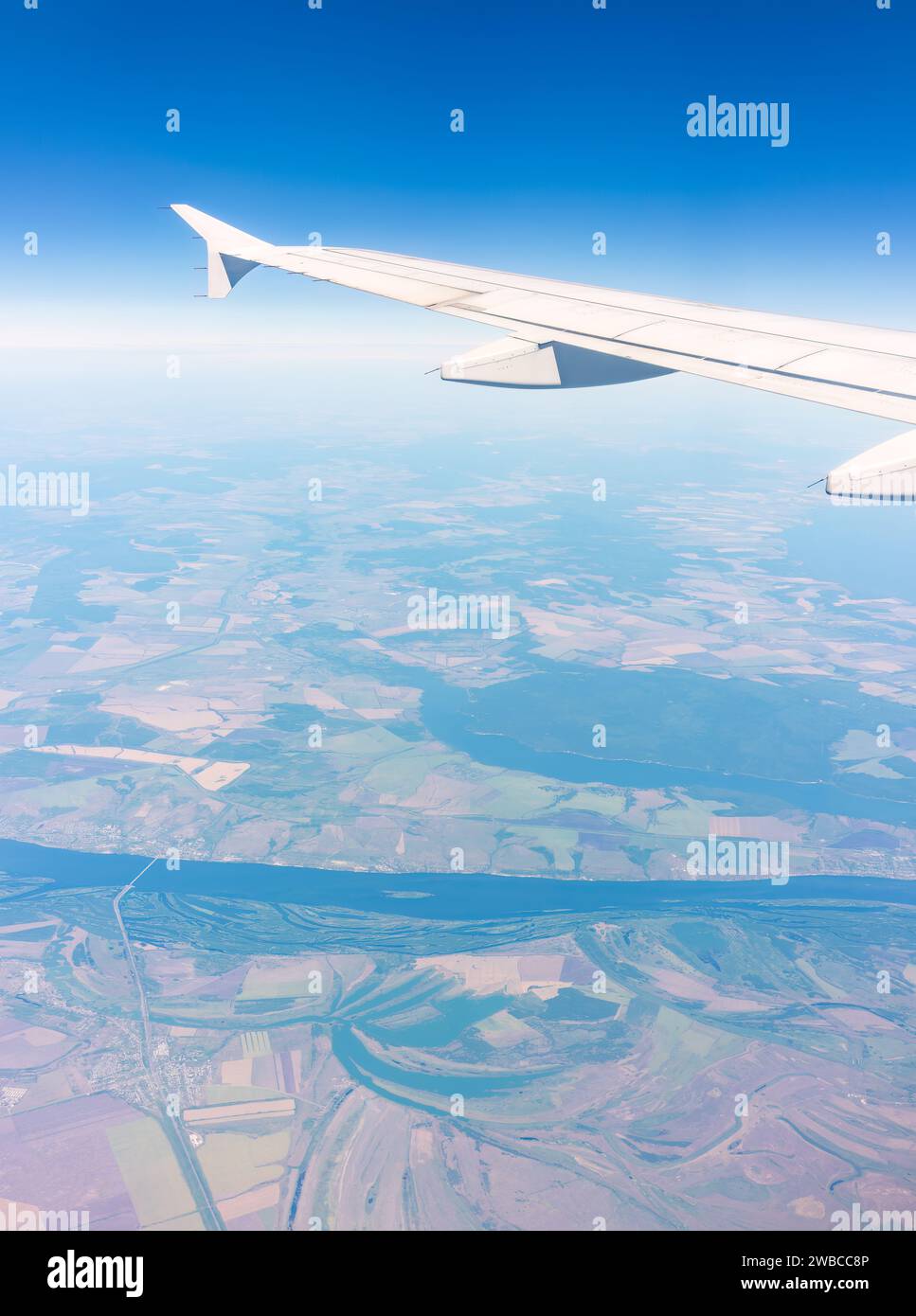 Aerial view from airplane window above green ground. View from the ...