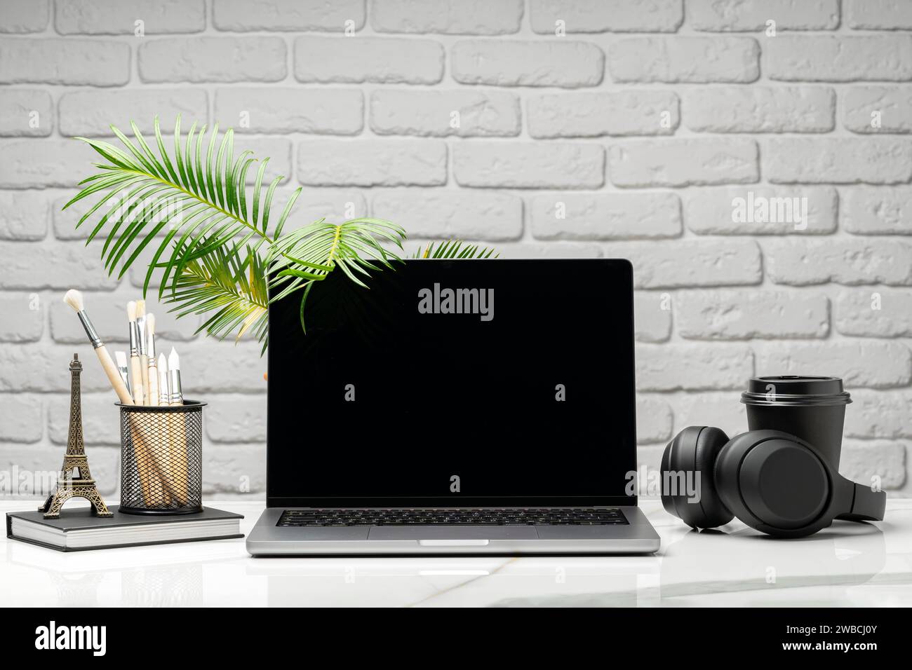 Laptop with black screen on desk against white brick wall Stock Photo ...