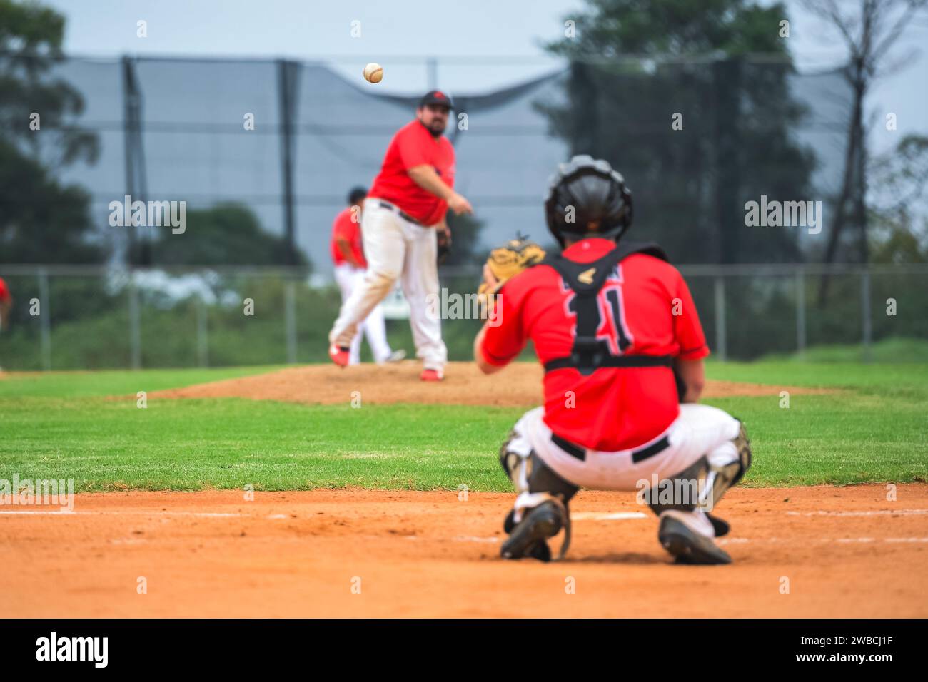 Men playing baseball game. Catcher is getting read to catch baseball ...