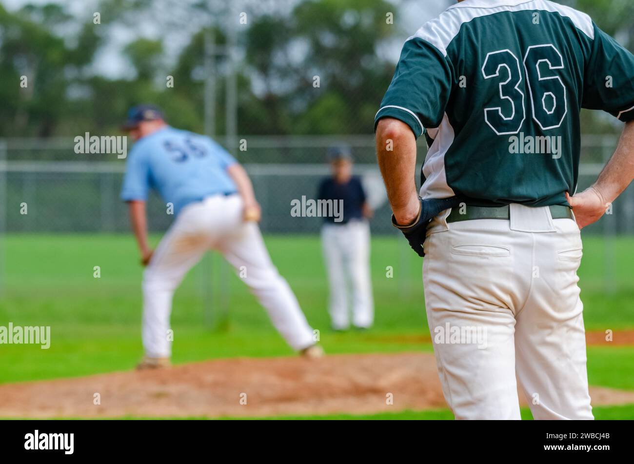 Baseball game, runner on the first base is watching the pitcher and ...