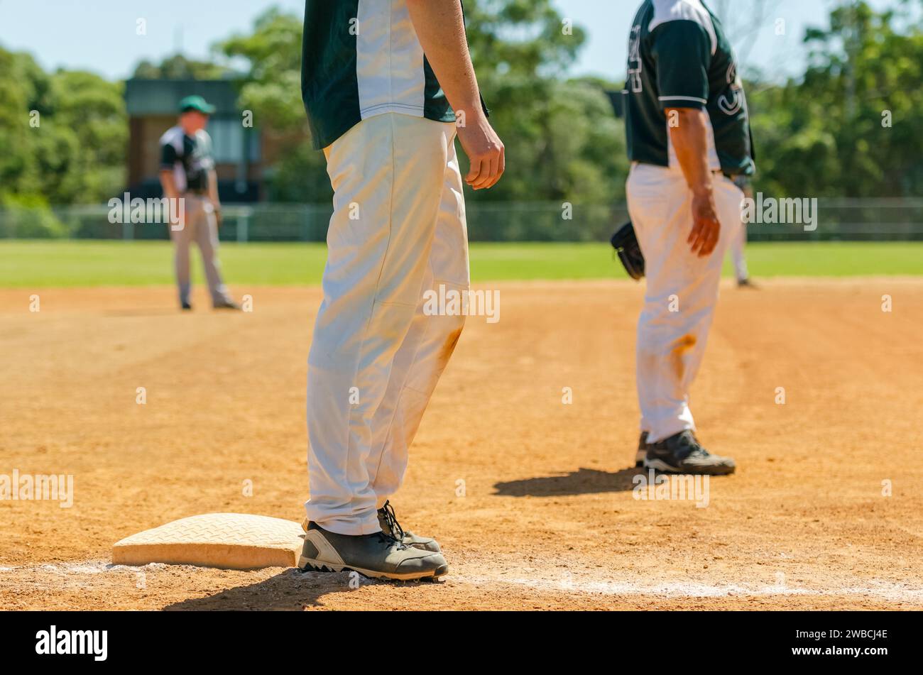 Baseball game, runner on the third base is watching the pitcher and ...