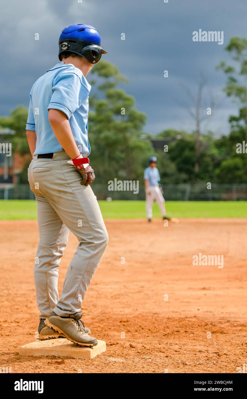 Baseball game, runner on the third base is watching the pitcher and ...