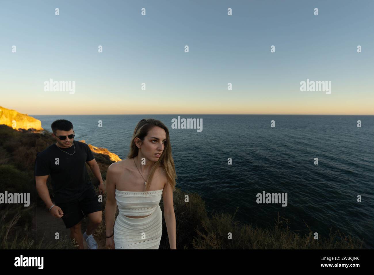 High-angle shot of young man and woman walking on a cliff overlooking ...