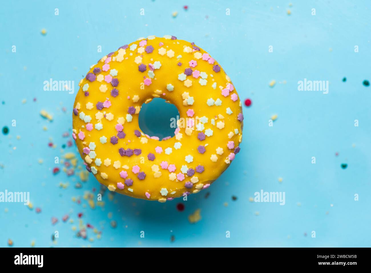 Donut with yellow glaze and colorful crumbs in the shape of a flower on ...