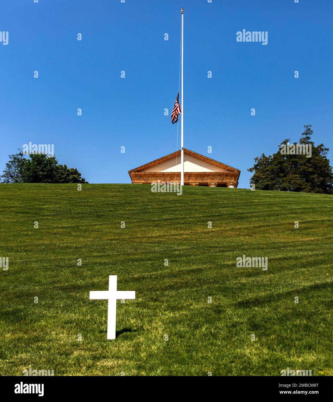A white marble cross tomb in front of the pantheon and house at ...