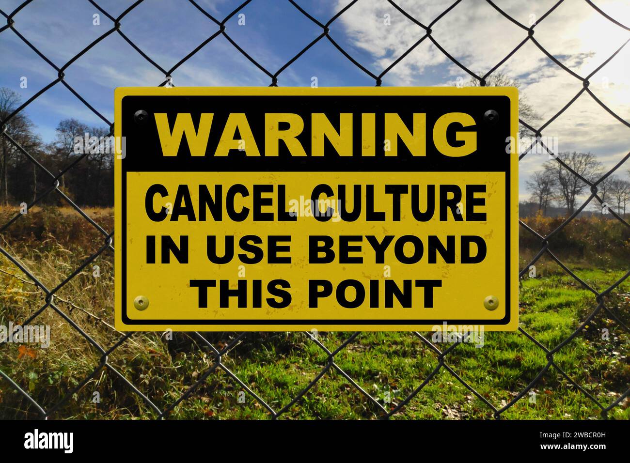 Black and yellow warning sign on a fence stating in "Warning - Cancel ...