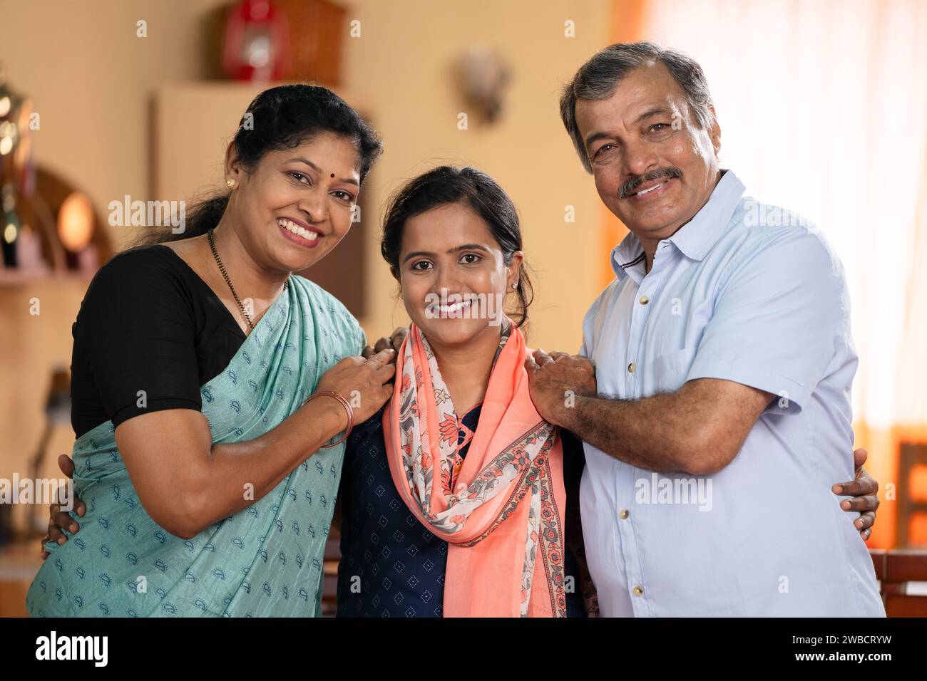Happy smiling Middle class parents with daughter looking camera at home ...