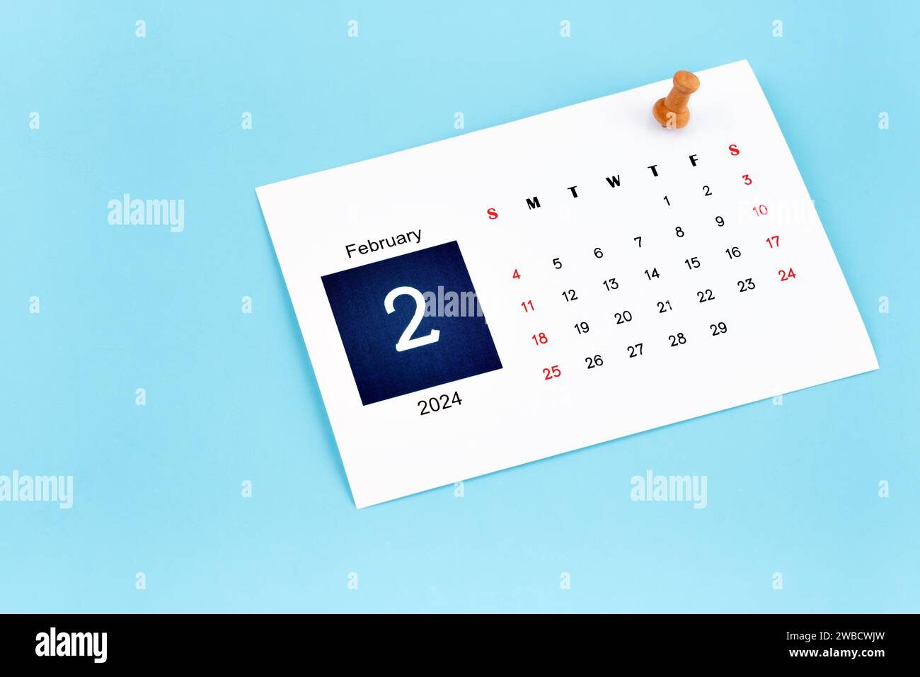 February 2024 calendar page with push pin on blue color background ...