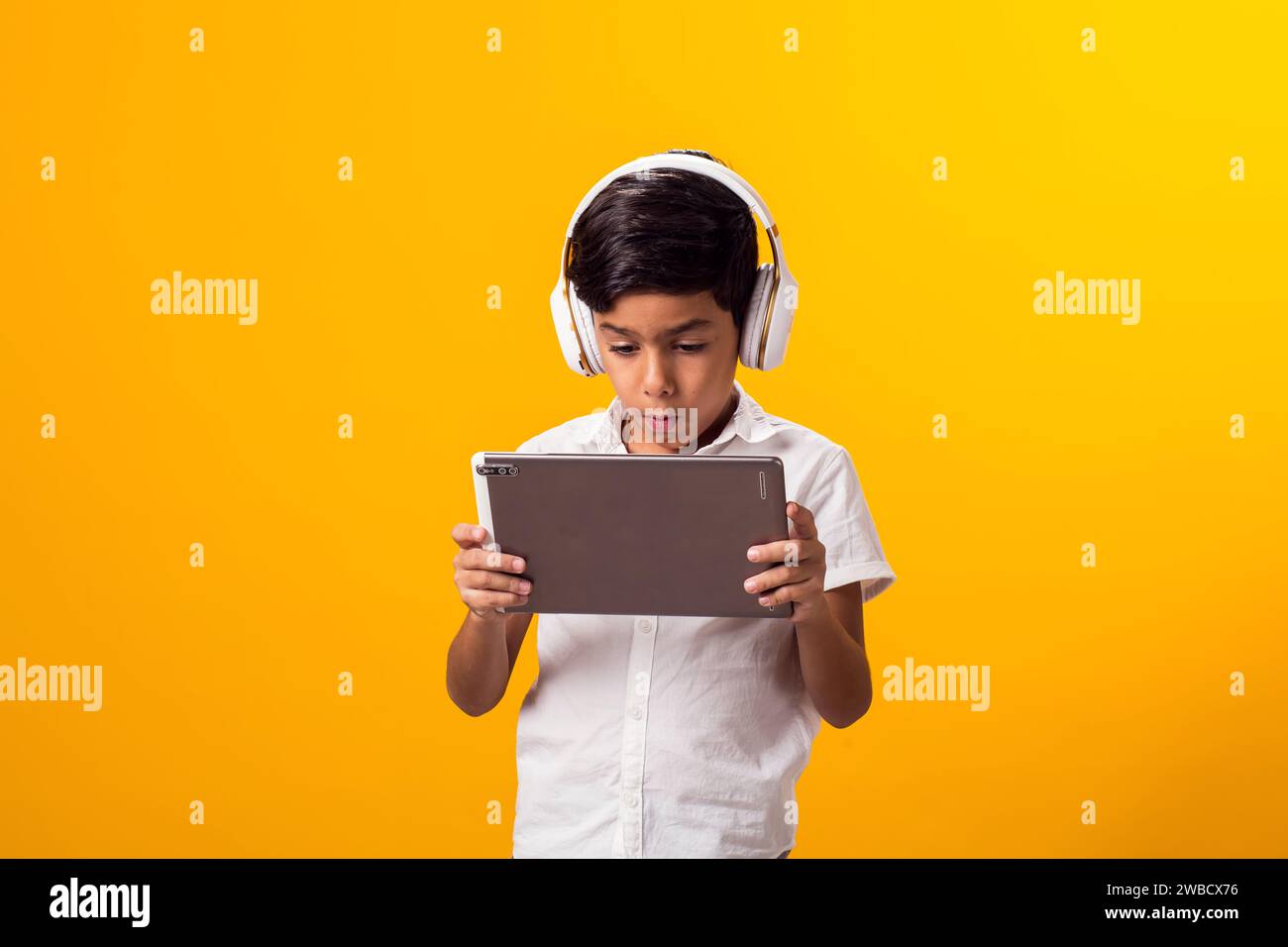 Portrait of kid boy with headphone and tablet playing video game ...