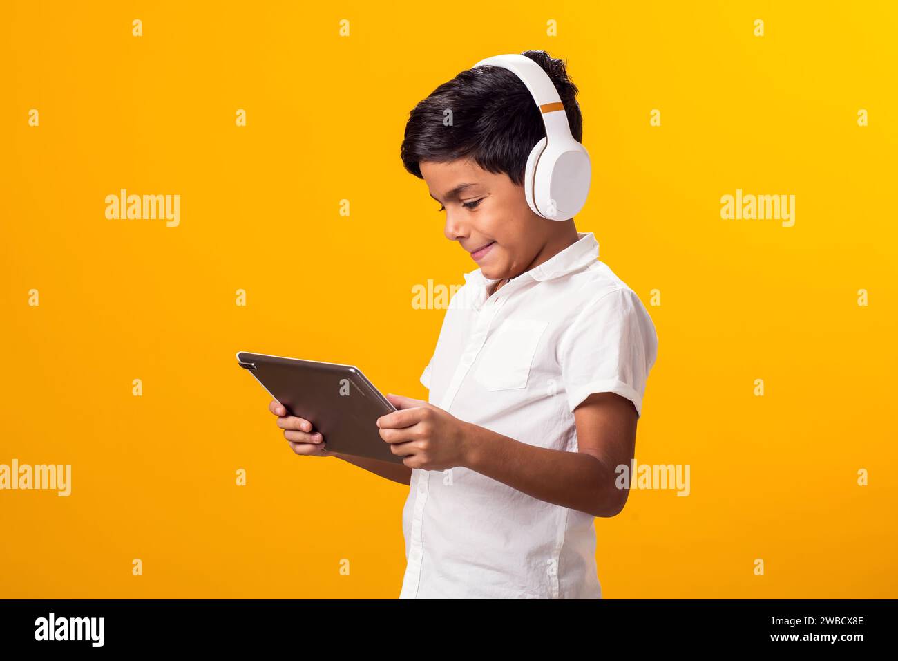 Portrait of kid boy with headphone and tablet playing video game ...
