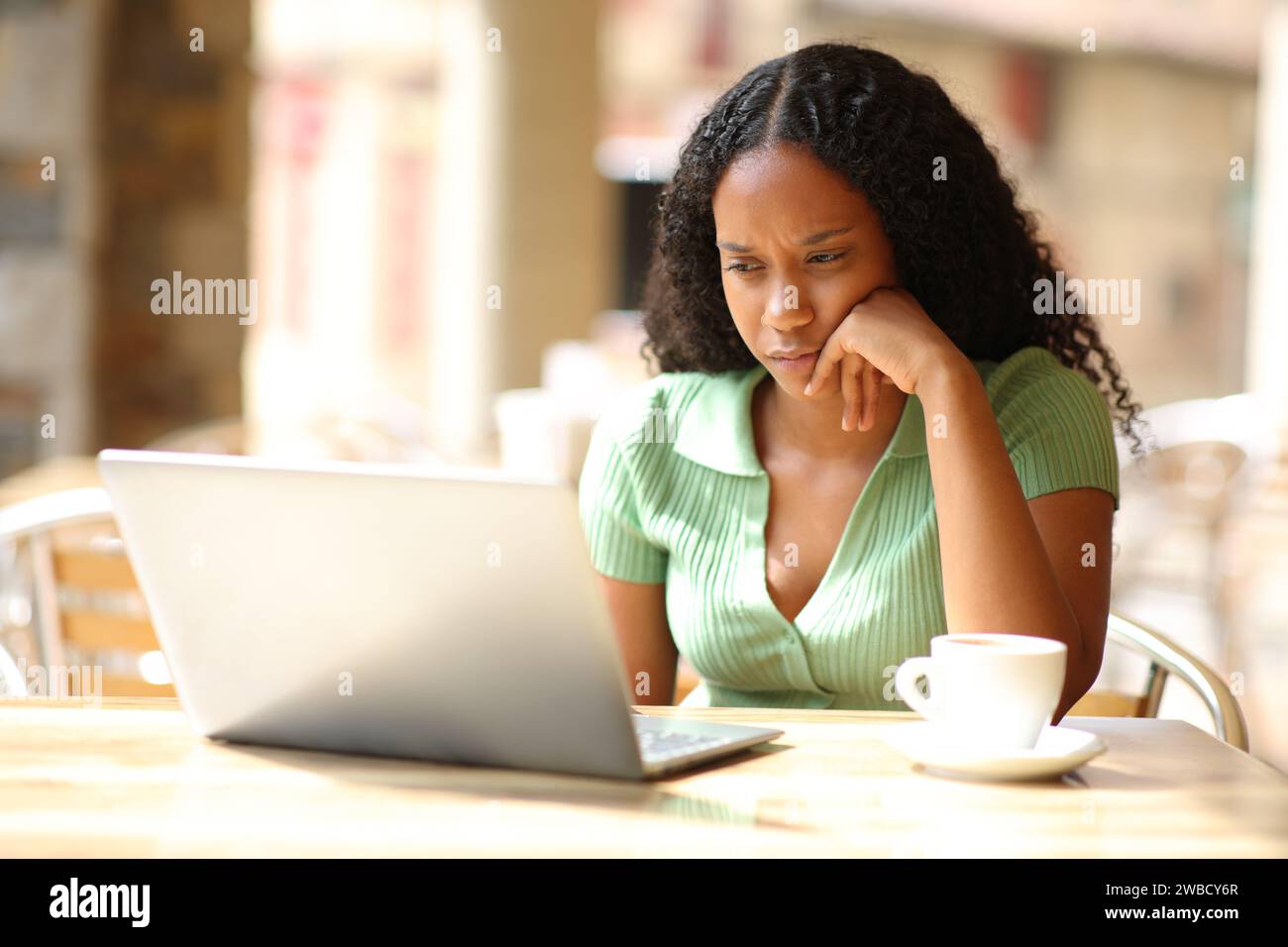Serious black woman checking laptop in a bar terrace Stock Photo - Alamy
