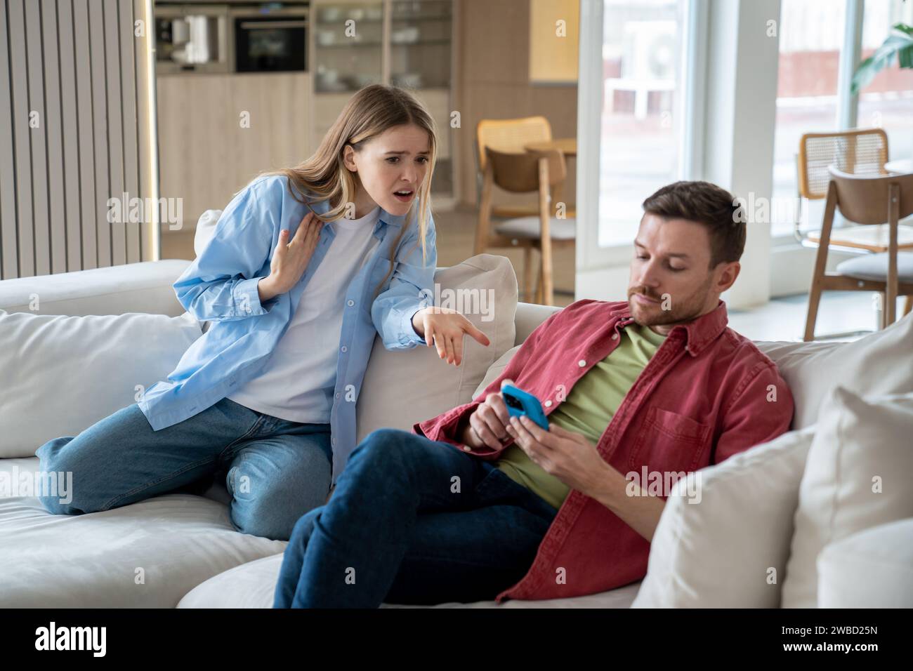 Offended wife reproaching uncaring husband in doing nothing, sitting ...