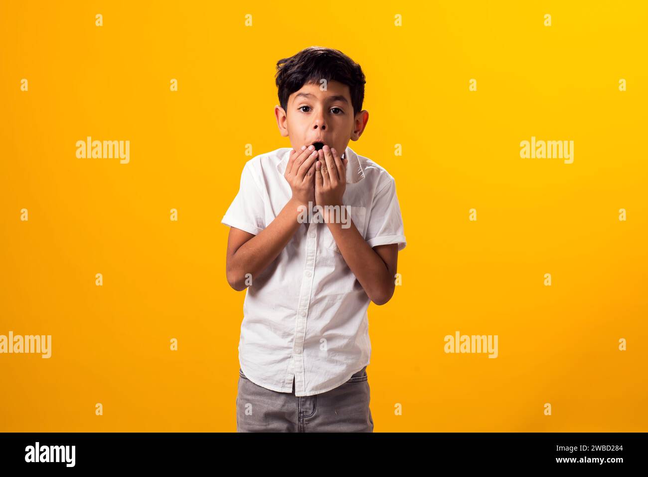 Portrait of surprised kid boy over yellow background. Astonished ...