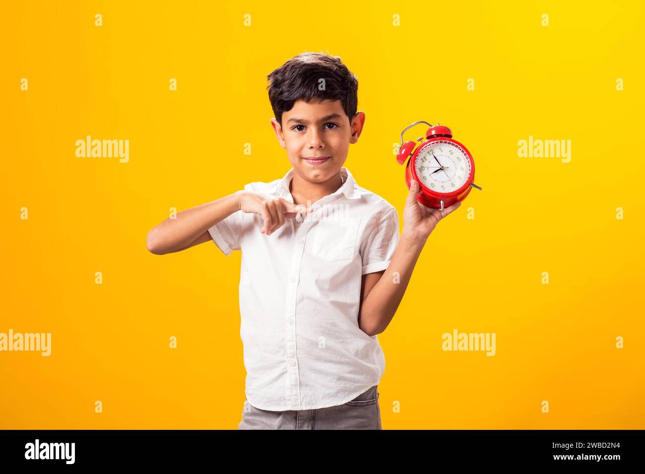 Portrait of kid boy holding alarm clock and pointing at it. Education ...