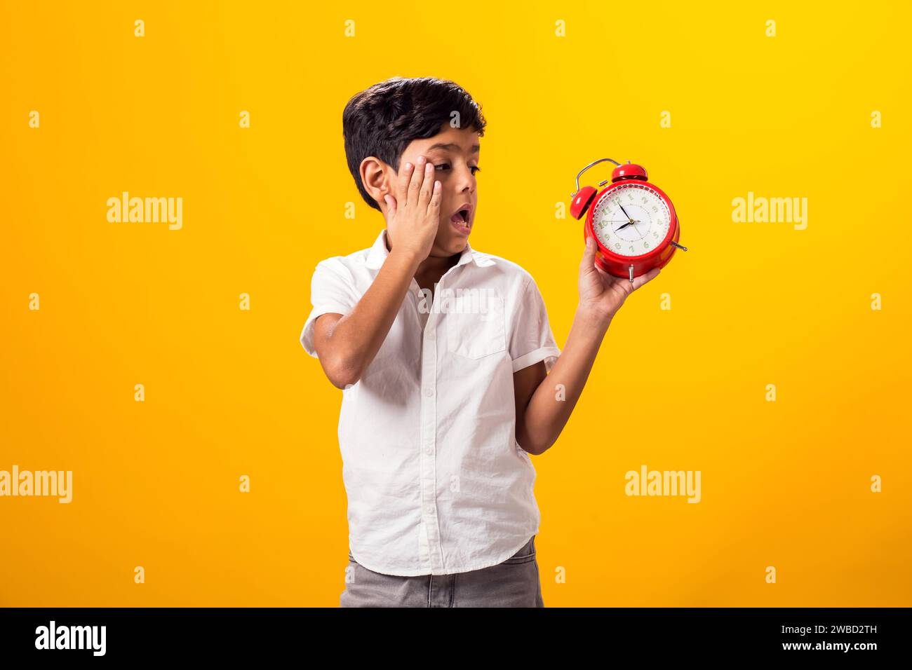 Portrait of surprised kid boy holding alarm clock. Education and time ...