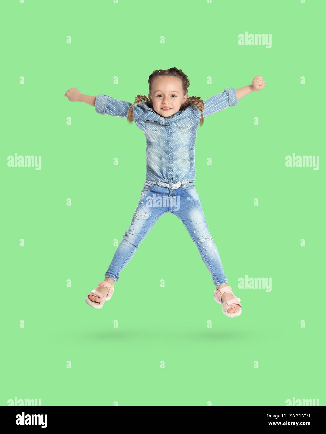 Happy cute girl jumping on light green background Stock Photo - Alamy